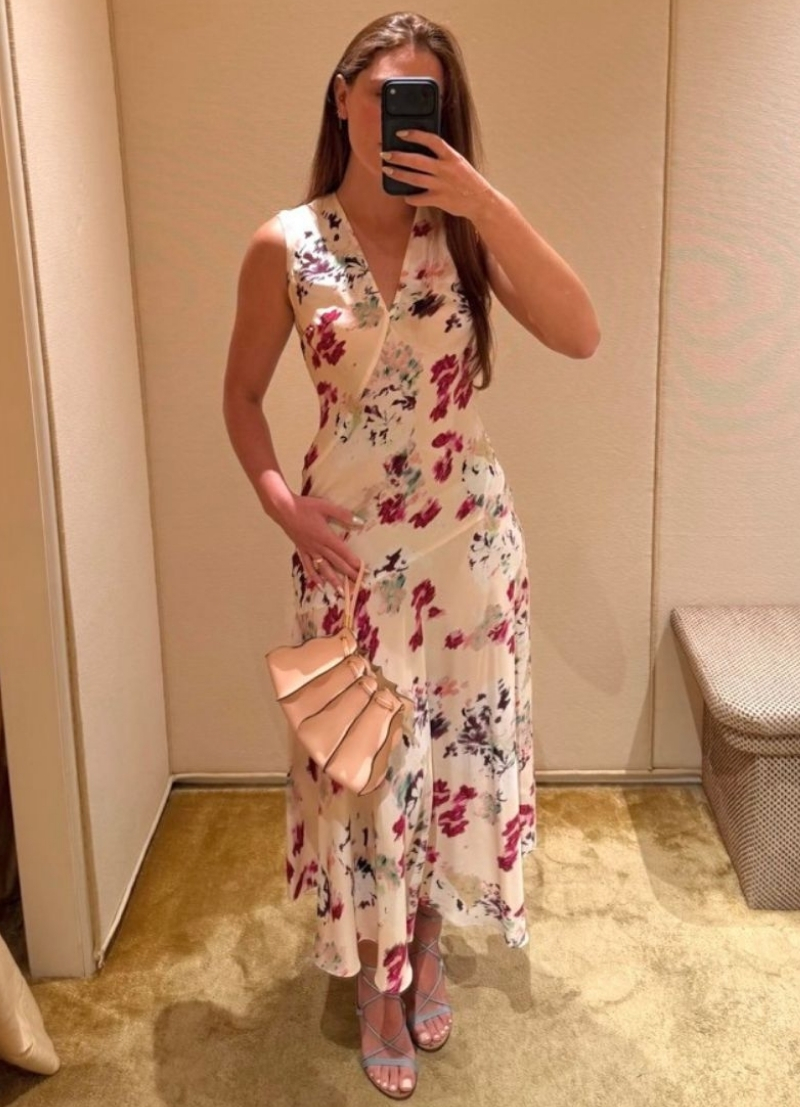 Mirror selfie featuring a cream floral midi dress with a blush clutch bag and lace-up heels in a fitting room