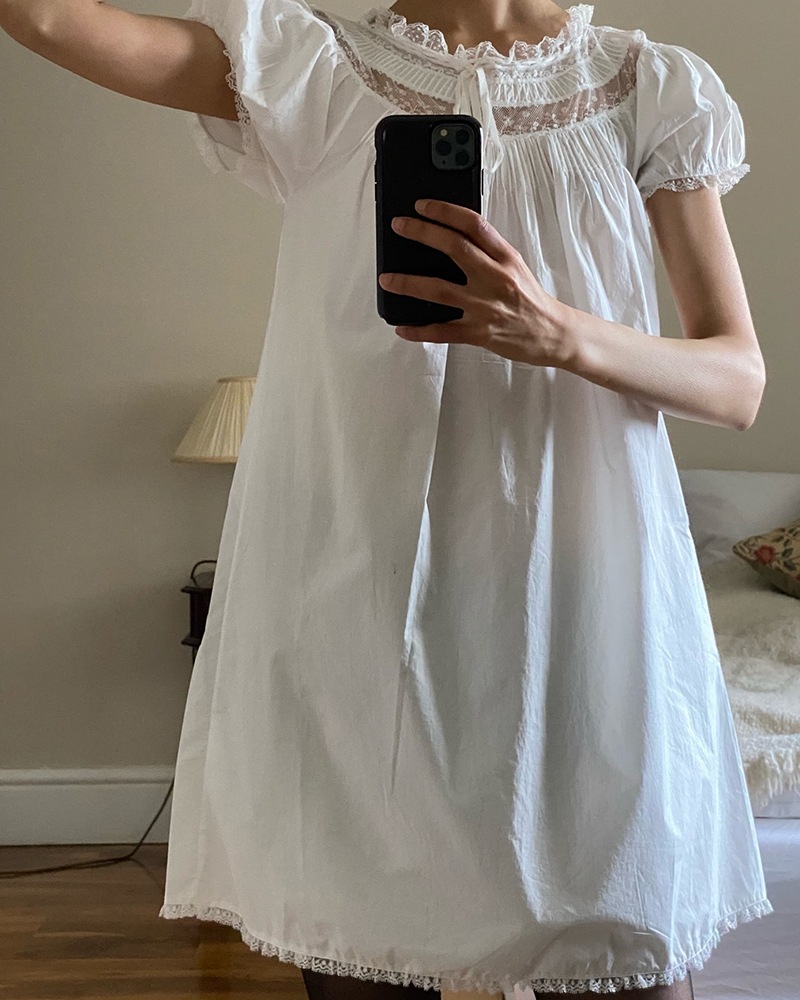 White cotton babydoll mini dress with lace-trim details and puff sleeves%2C styled in a soft bedroom mirror selfie setting