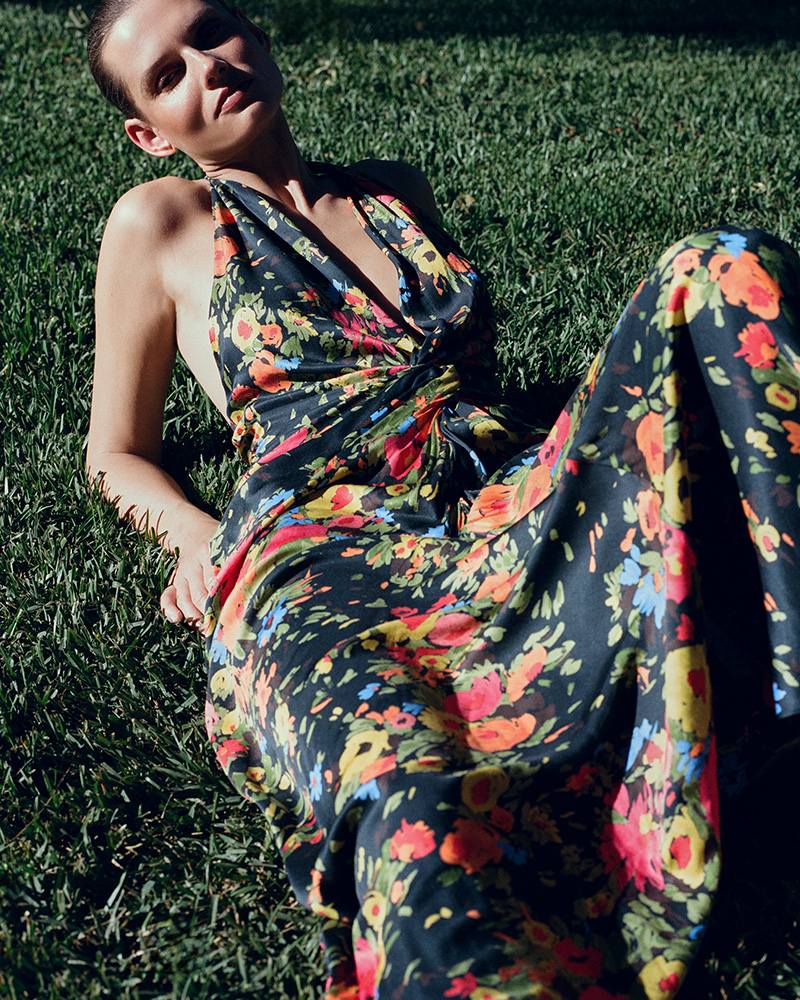 Sleeveless floral halter maxi dress with draped neckline and vibrant print%2C styled on sunlit grass for a summer garden look