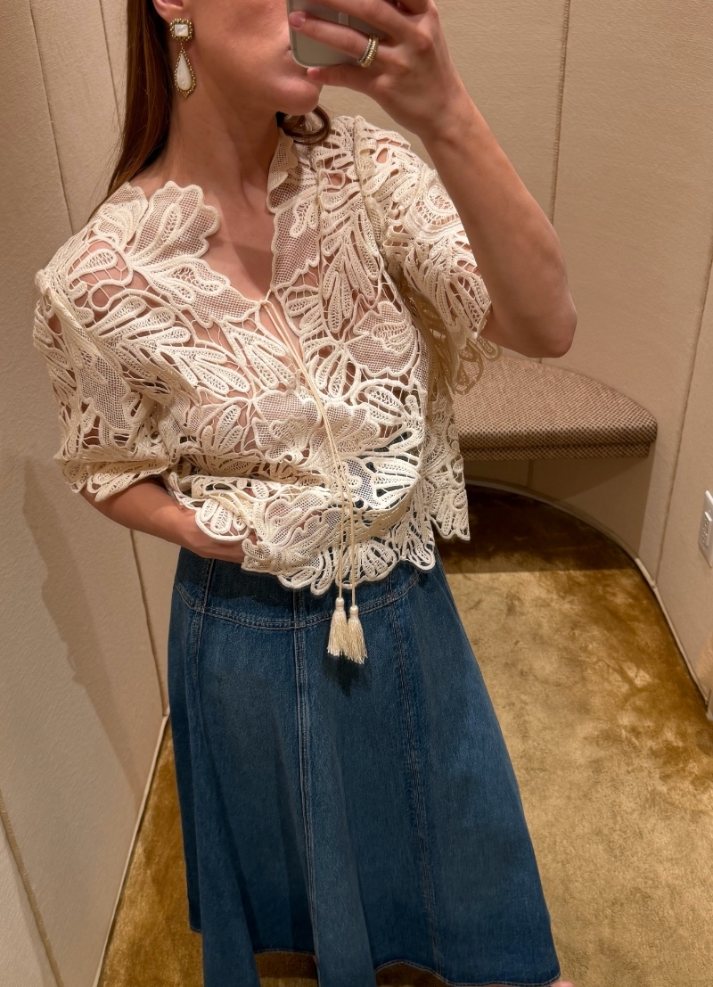 Cream floral lace blouse with tassel ties and a denim midi skirt, styled in a boutique fitting room mirror selfie