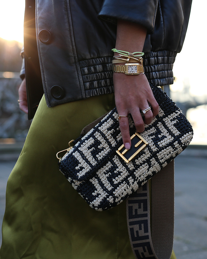 Fendi Baguette woven shoulder bag with FF logo%2C gold Cartier watch%2C and leather jacket styled for a city street look
