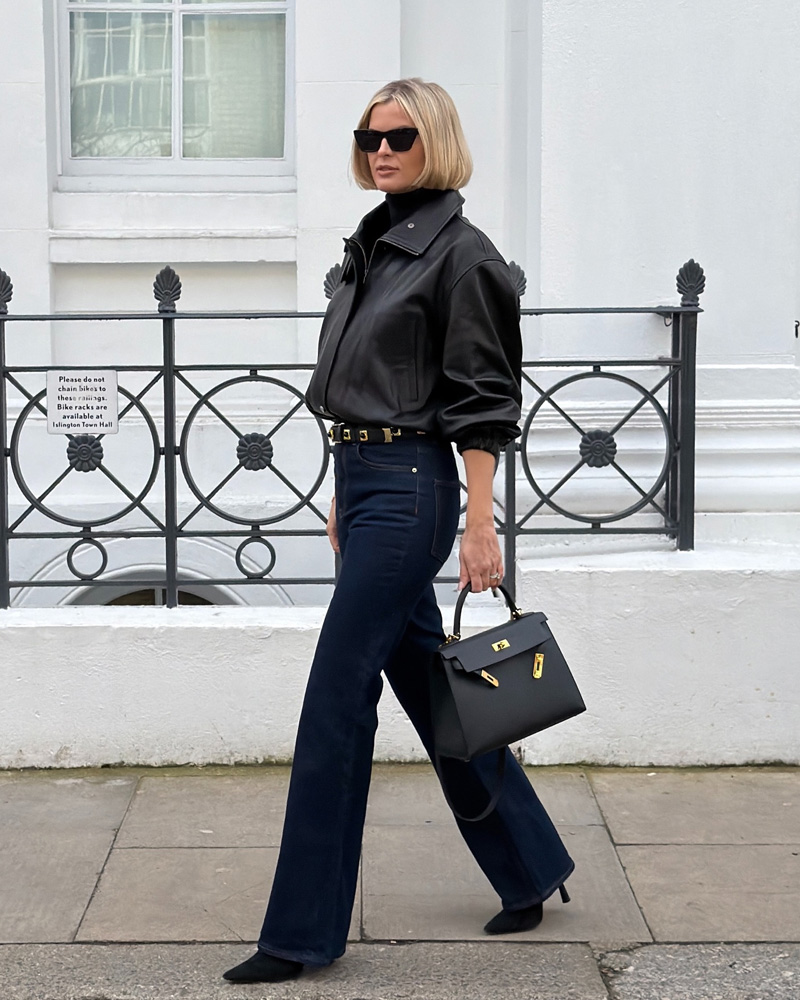 Herm%C3%A8s Kelly handbag styled with a black leather jacket%2C wide-leg dark jeans%2C and cat-eye sunglasses on a city sidewalk