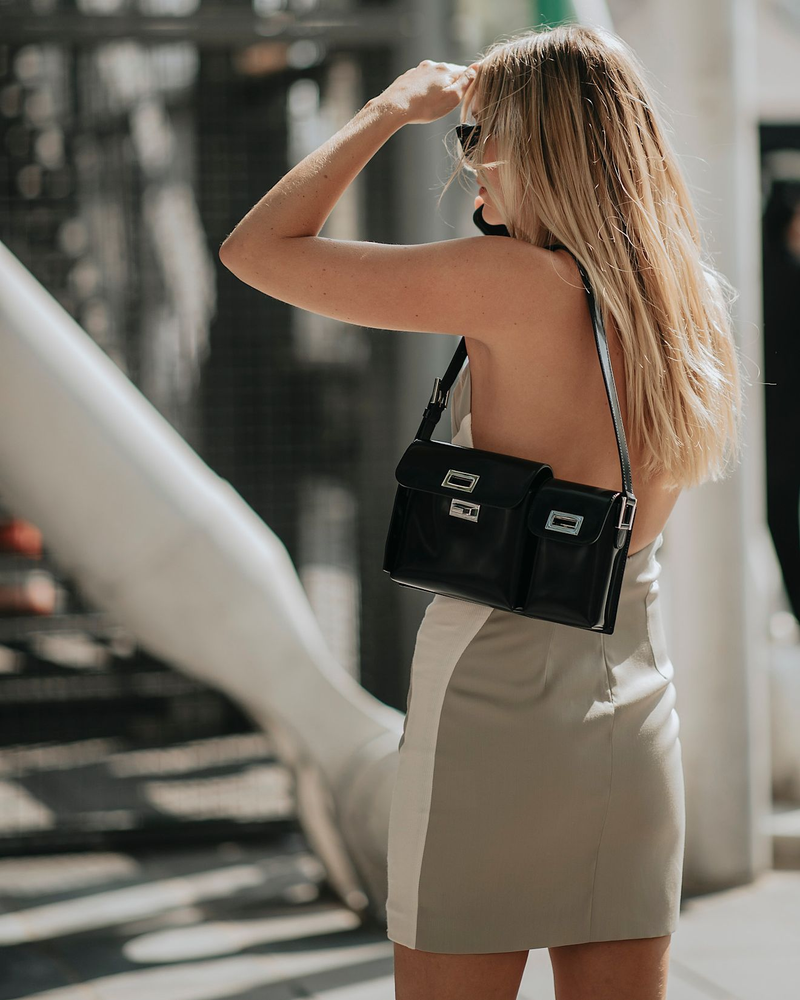 Backless beige mini dress paired with a black leather shoulder bag featuring silver hardware%2C styled for spring-summer fashion