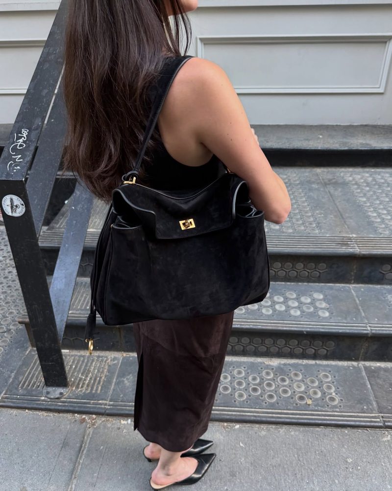 Chic black suede tote bag with a stylish gold clasp%2C paired with a sleek black sleeveless top and brown midi skirt%2C showcasing modern elegance