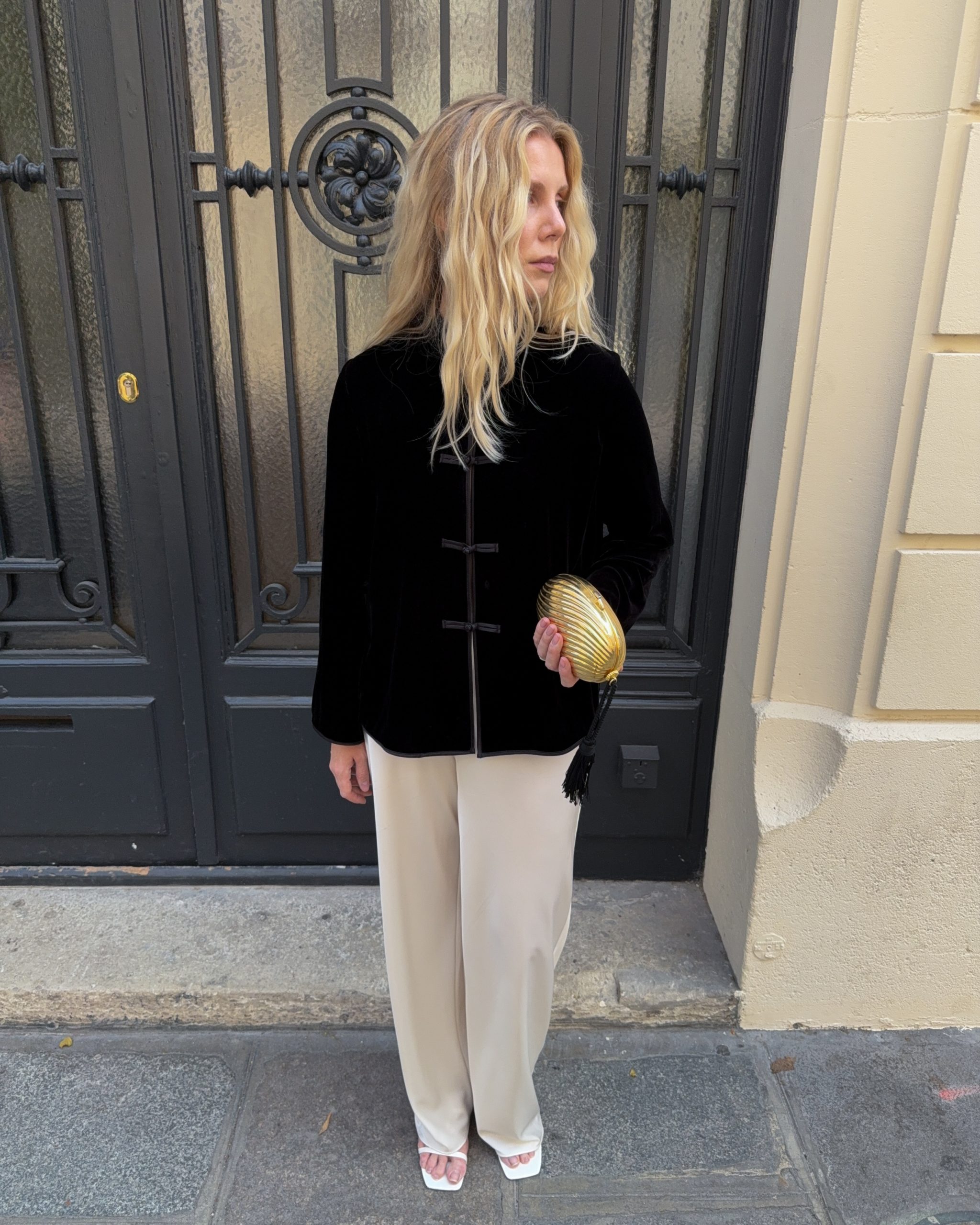 Chic black velvet jacket with a high collar%2C paired with cream wide-leg trousers and gold clutch%2C styled for a sophisticated outing in Le Marais
