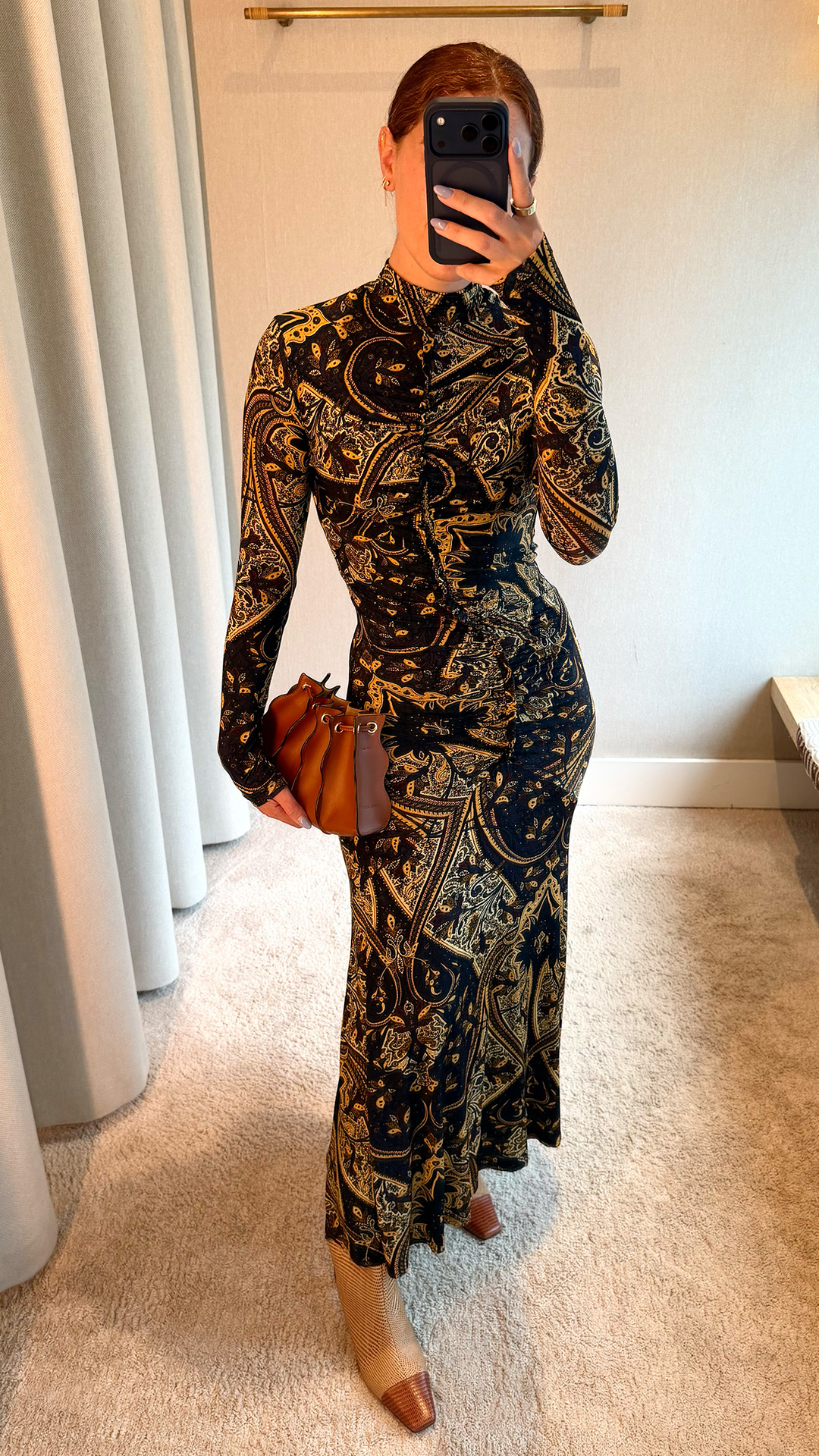 Paisley maxi dress styled with a brown leather drawstring bag and two-tone pointed flats in a fitting room