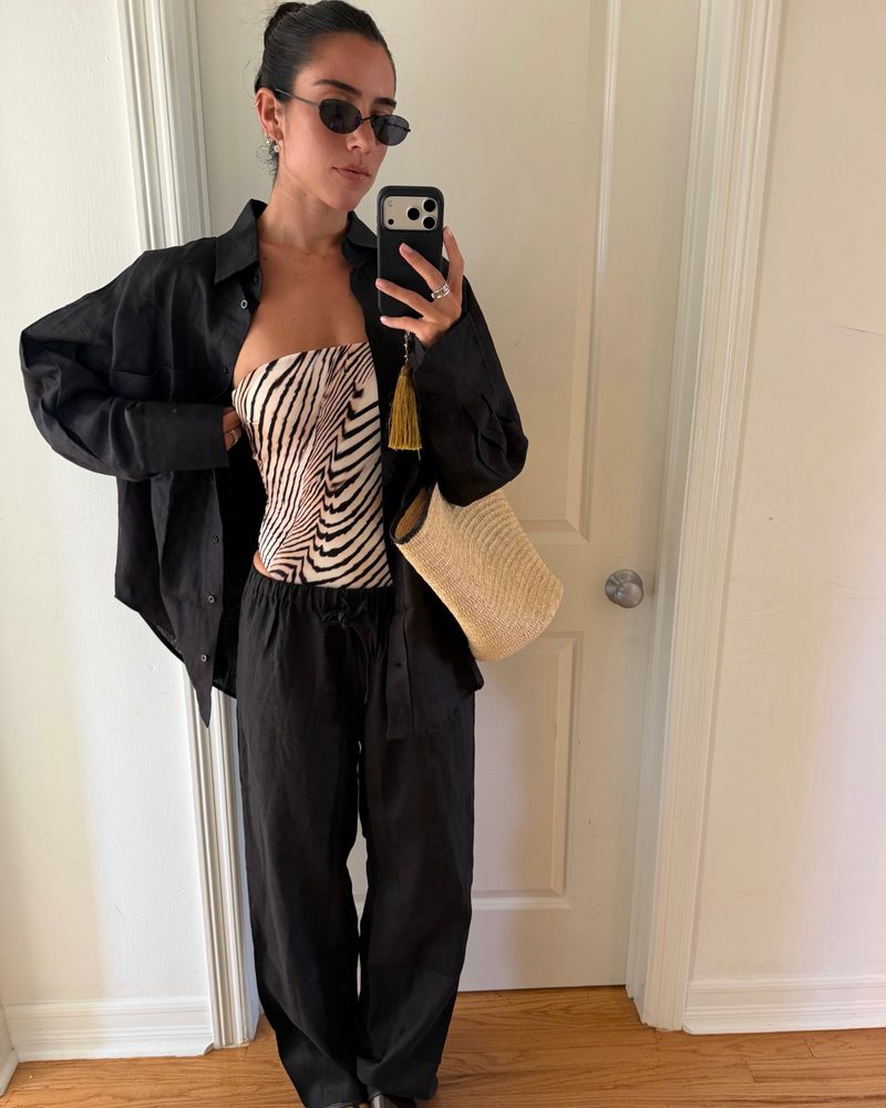 Black oversized linen shirt and pants paired with a zebra print strapless top%2C black sandals%2C round sunglasses%2C and a woven straw tote bag