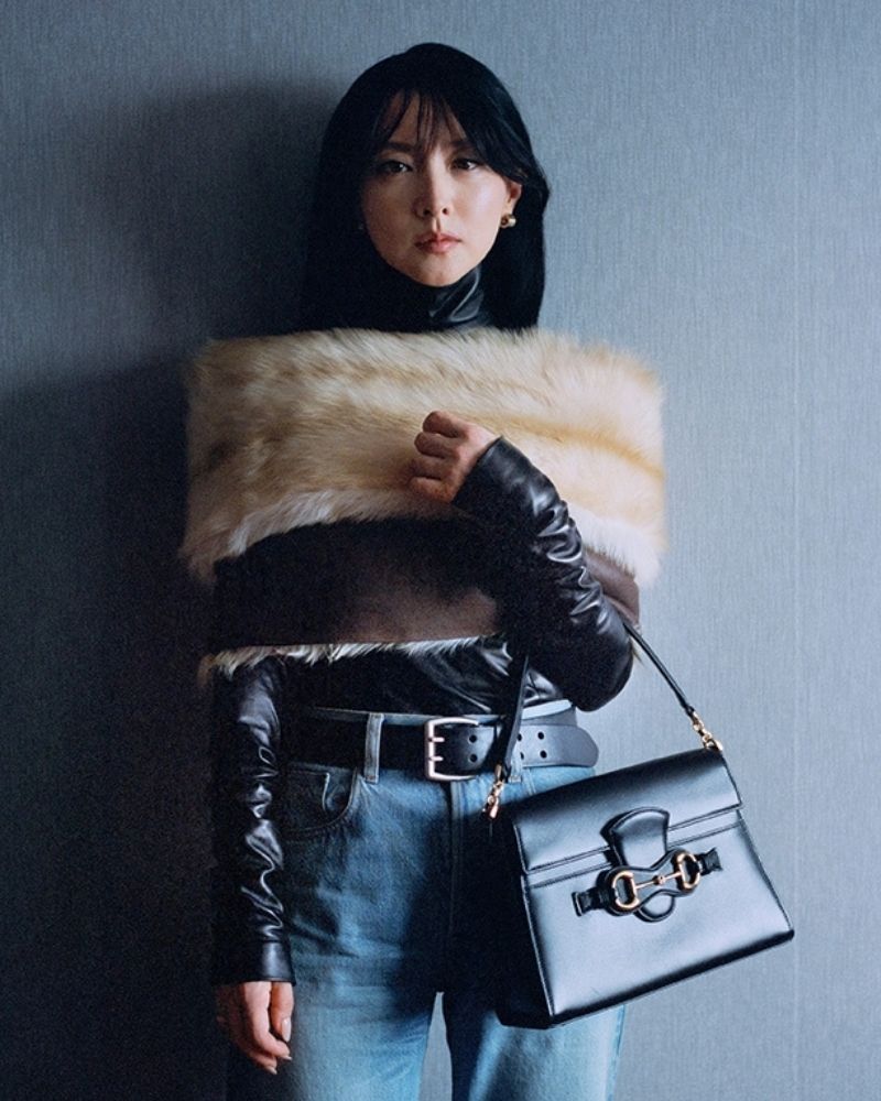 Gucci-inspired look pairs a cream faux-fur stole and black leather gloves with blue jeans and a structured black handbag%0A
