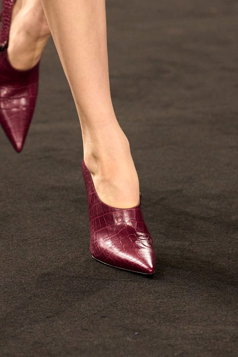Pointed-toe burgundy leather mule shoes with crocodile texture on runway