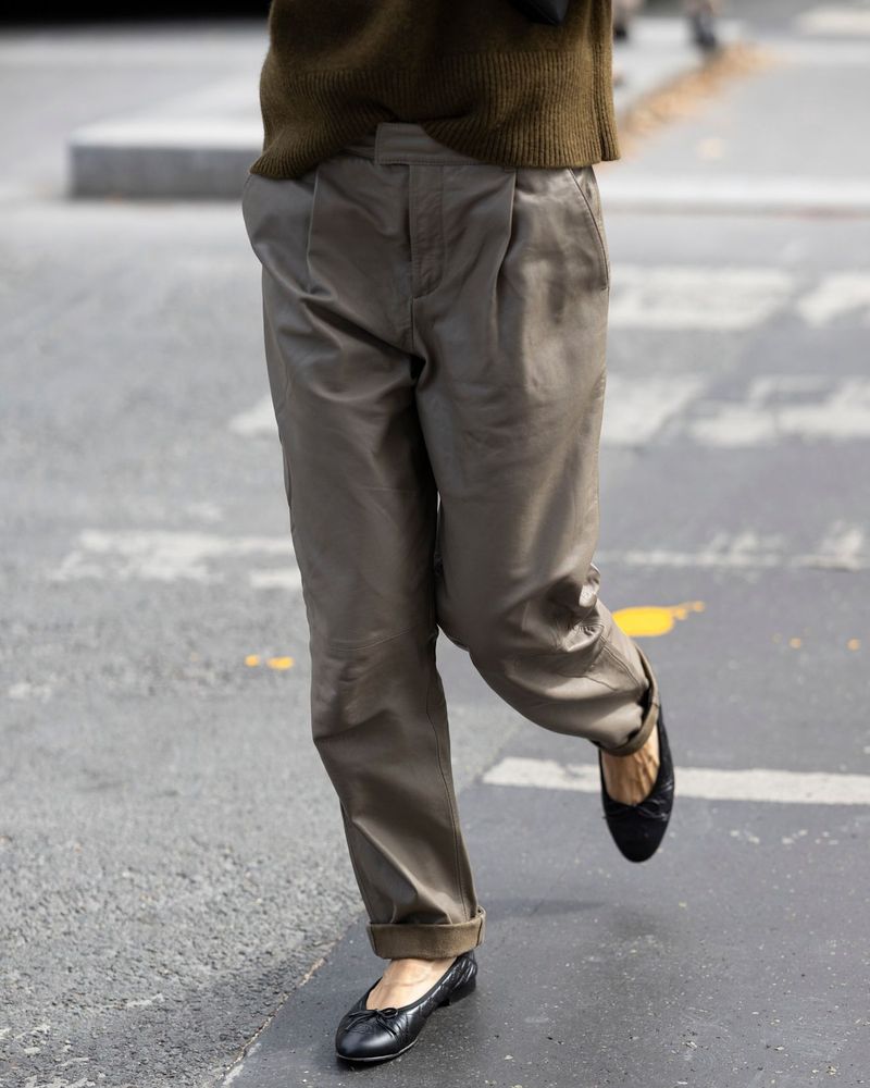 Relaxed fit taupe leather trousers paired with black ballet flats and a brown knit sweater for fall street style