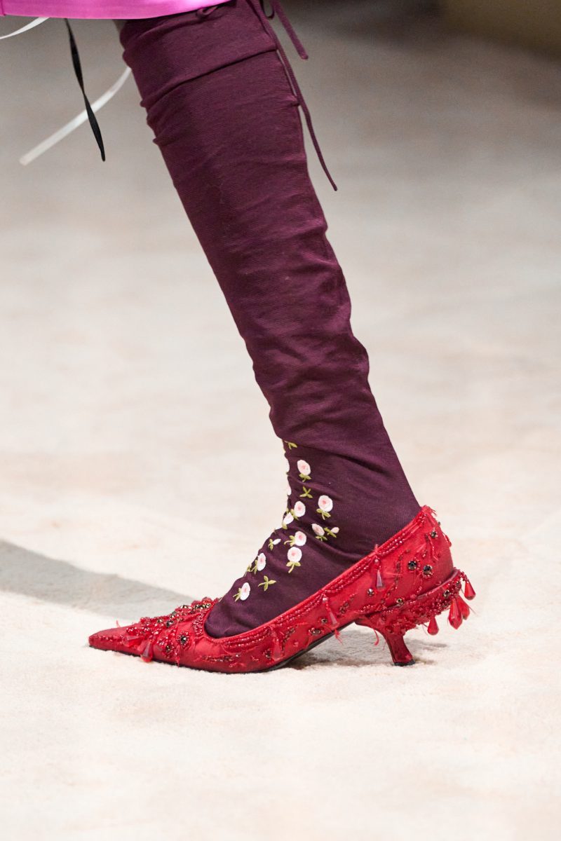 Red embellished kitten heel shoes paired with purple floral embroidered tights for a bold runway look