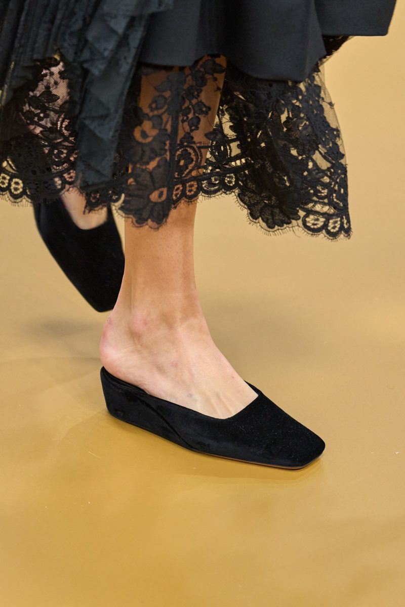 Black velvet wedge mules paired with a black lace-trimmed midi skirt showcasing elegant fall fashion details