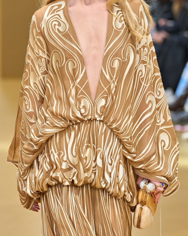 Zimmermann flowy printed dress in warm beige features intricate swirling patterns%2C with a deep V-neck and cinched waist detail%2C perfect for fall styling