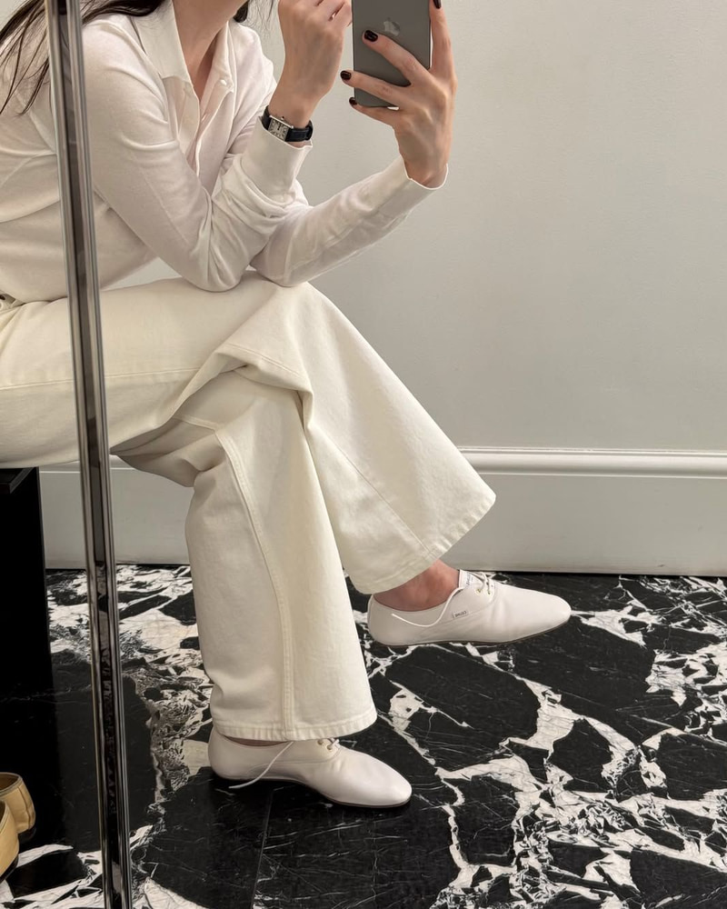 Chic outfit featuring a slim-fit white blouse and wide-leg white pants%2C paired with elegant Celine leather shoes on a marble floor