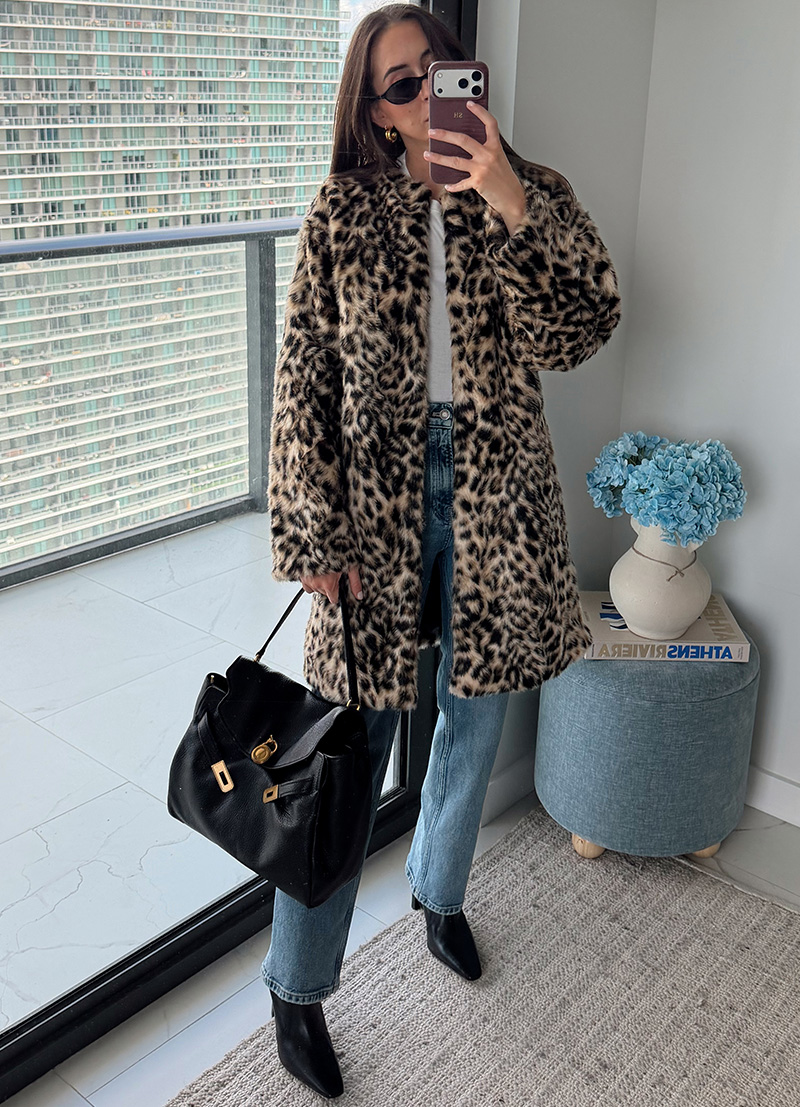 Leopard-print faux-fur coat styled with blue jeans, black pointed boots, and an oversized black leather handbag