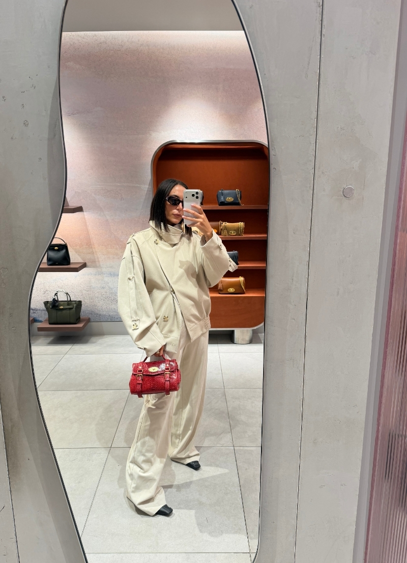 Cream oversized jacket and wide-leg trousers paired with a red textured top-handle bag in a boutique