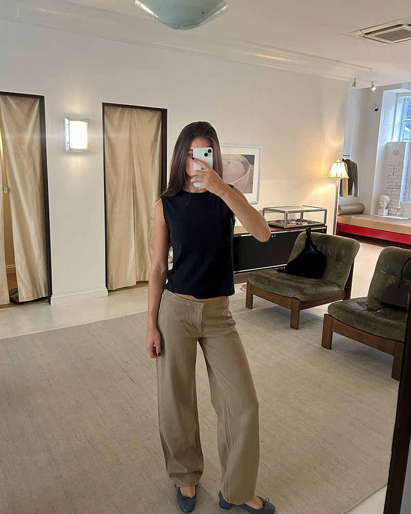 Black sleeveless top with khaki wide-leg jeans and blue ballet flats styled in a minimalist boutique interior