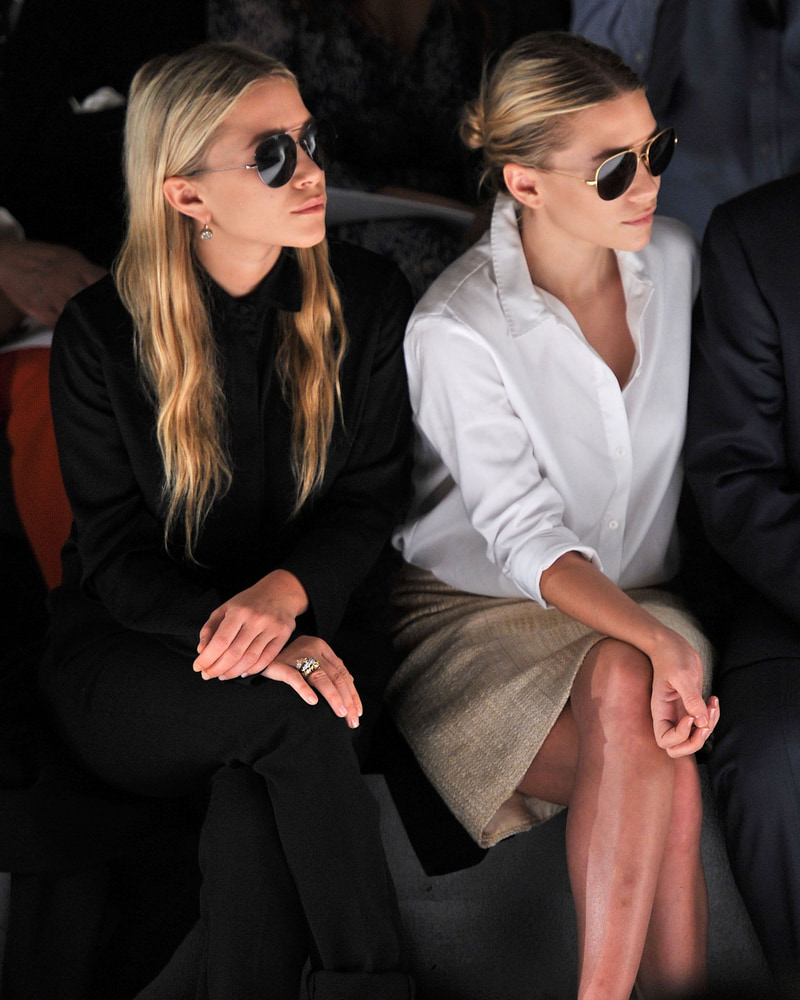 Olsen twins showcase effortless style at a fashion event%2C one in a chic black ensemble and the other in a white shirt paired with a beige skirt
