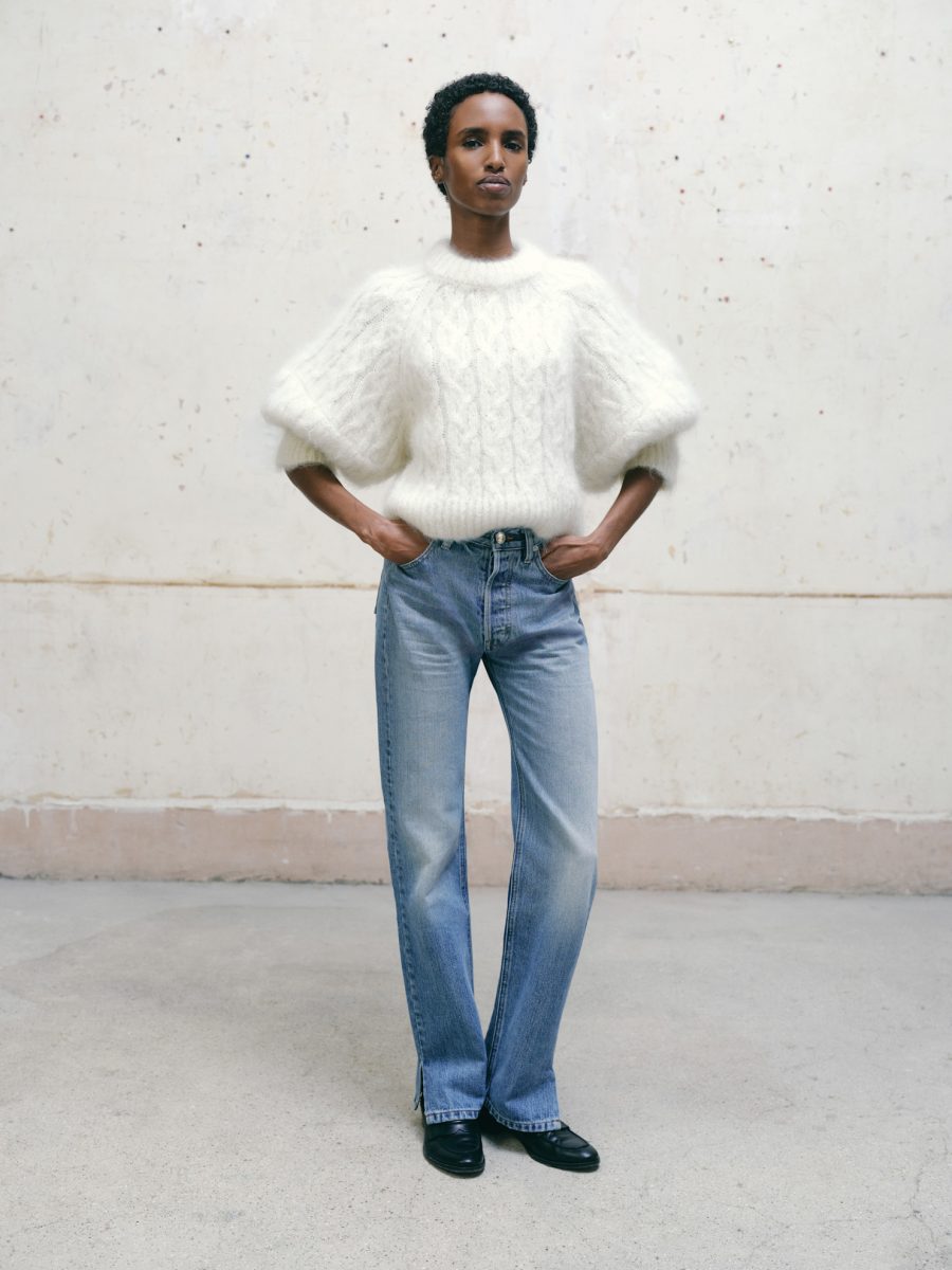 Model wearing a white fluffy cable-knit sweater with puffed sleeves paired with high-waisted light blue straight-leg jeans and black loafers