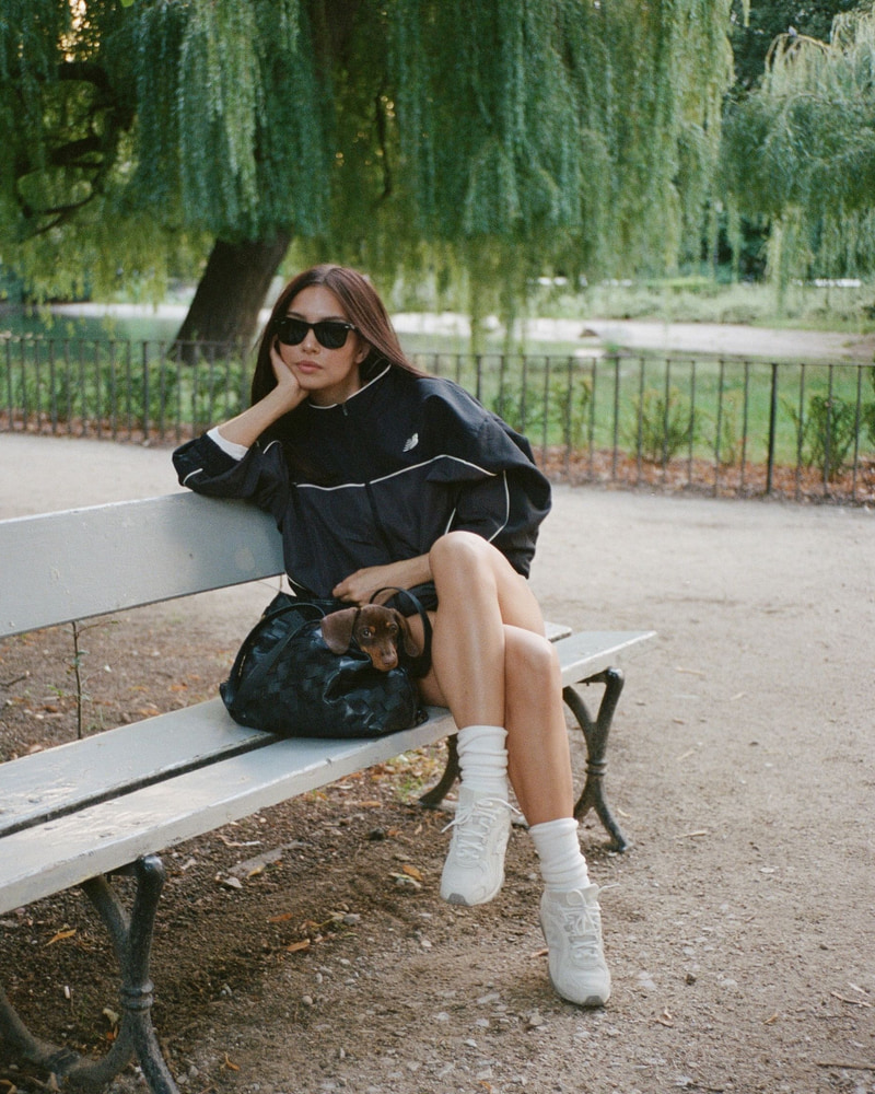 Cozy athleisure look featuring a black zip-up windbreaker%2C white ankle socks%2C and chunky sneakers%2C paired with a stylish tote bag and a small dog.