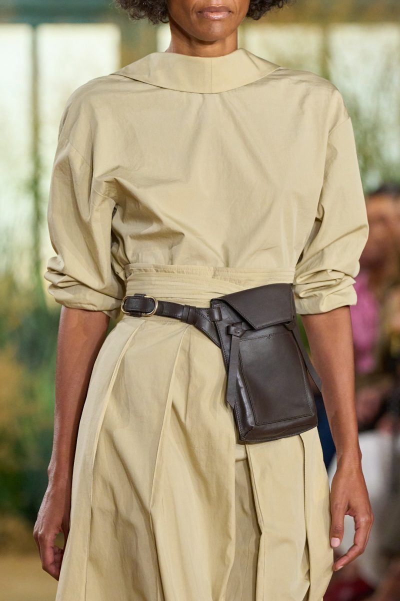 Beige cotton dress with rolled sleeves paired with a dark brown leather belt bag for a chic, utilitarian look