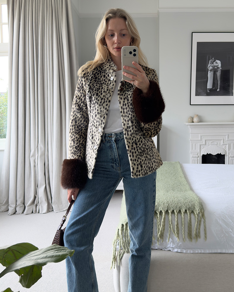 Leopard-print jacket with dark fur cuffs styled over a white tee and blue jeans in a bedroom mirror selfie