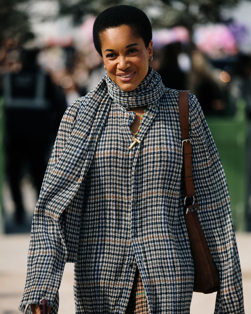 Smiling model wearing a navy and beige houndstooth wool blazer with matching scarf and brown leather shoulder bag in Paris street style